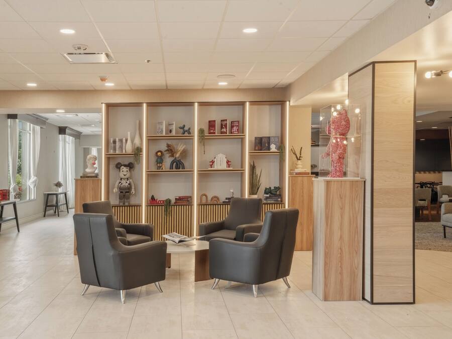 Um interior moderno com balcão de recepção, área de estar e estante com diversos objetos decorativos.