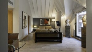Quarto de hotel moderno com uma cama grande, uma mesa de centro de vidro e obras de arte nas paredes.