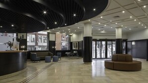Um hall moderno com balcão de recepção, área de estar e grandes janelas.