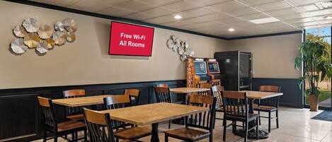 Restaurante com mesas e cadeiras, um letreiro vermelho indicando Wi-Fi gratuito e uma decoração na parede.