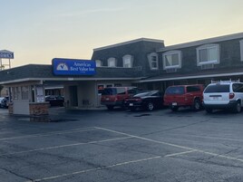 Um estacionamento com vários carros estacionados em frente a um edifício com a placa "Americas Best Value Inn by Vantage".