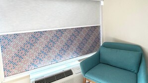 Um quarto com parede estampada, teto branco e poltrona azul-turquesa.