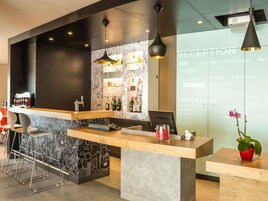 Uma área de recepção com bar, assentos e uma tela de projeção exibindo informações.