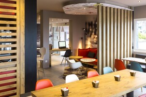 Um café moderno com detalhes em madeira, diversas opções de assento e uma mesa central com cestos.