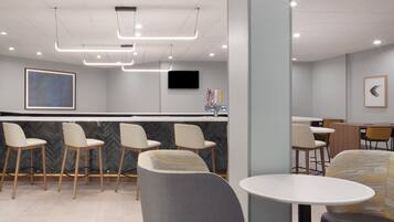 Um restaurante moderno com balcão, banquetas e uma televisão.