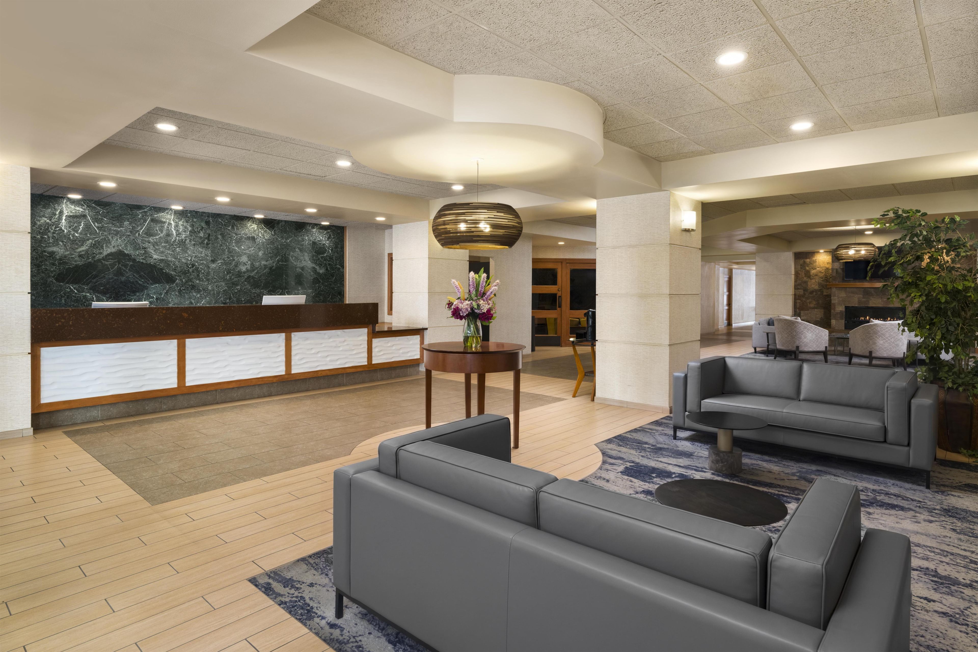 Um lobby moderno com balcão de recepção, área de estar e lareira.