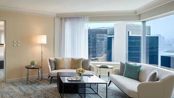 Quarto de hotel moderno com uma janela ampla que oferece vista para a cidade, um sofá, uma mesa de centro e um abajur.