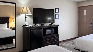 Quarto de hotel com cama, televisão, micro-ondas e cómoda.