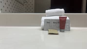 Uma bancada de banheiro com uma toalha branca, um tubo de loção corporal e uma caixa de demaquilante.
