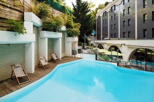 Piscina com espreguiçadeiras e vista para um edifício com varandas.