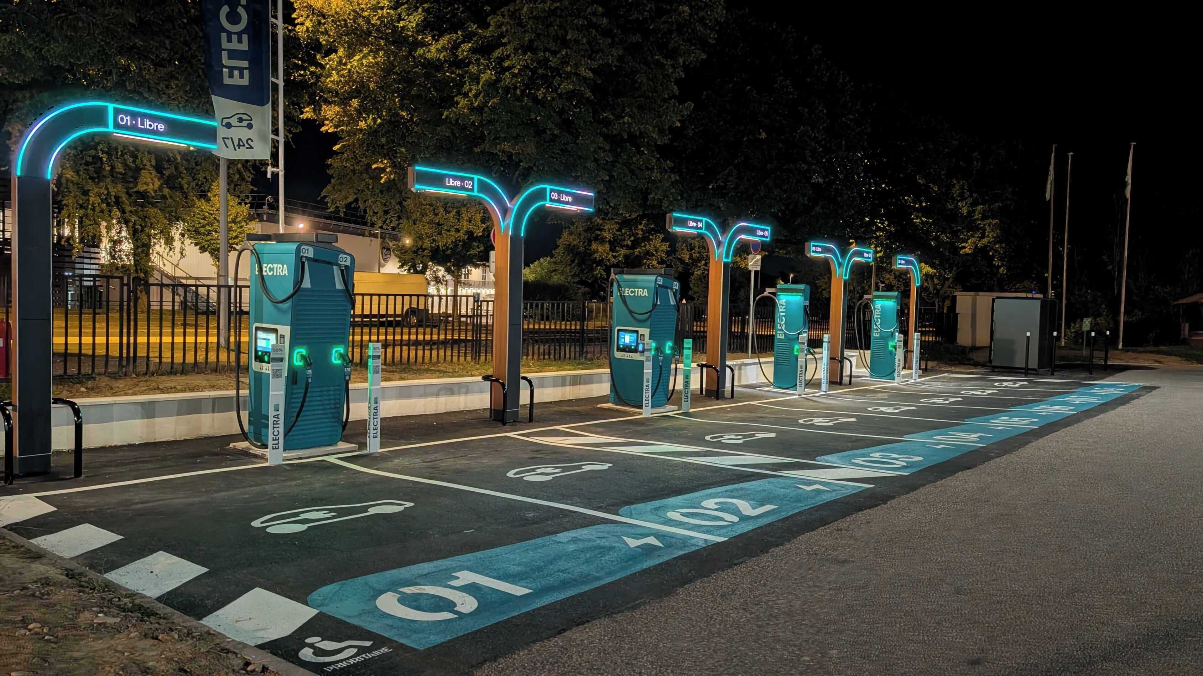 Uma fileira de estações de carregamento para veículos elétricos, com sinalização iluminada, cada uma identificada com um número.