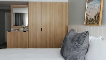 Quarto com cama, guarda-roupa espaçoso, espelho e quadro pendurado na parede.