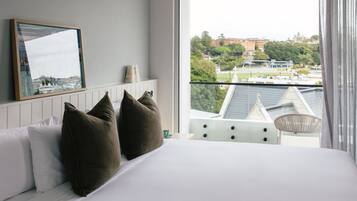 Quarto de hotel com uma cama grande, vista para a paisagem urbana e uma janela com cortinas.