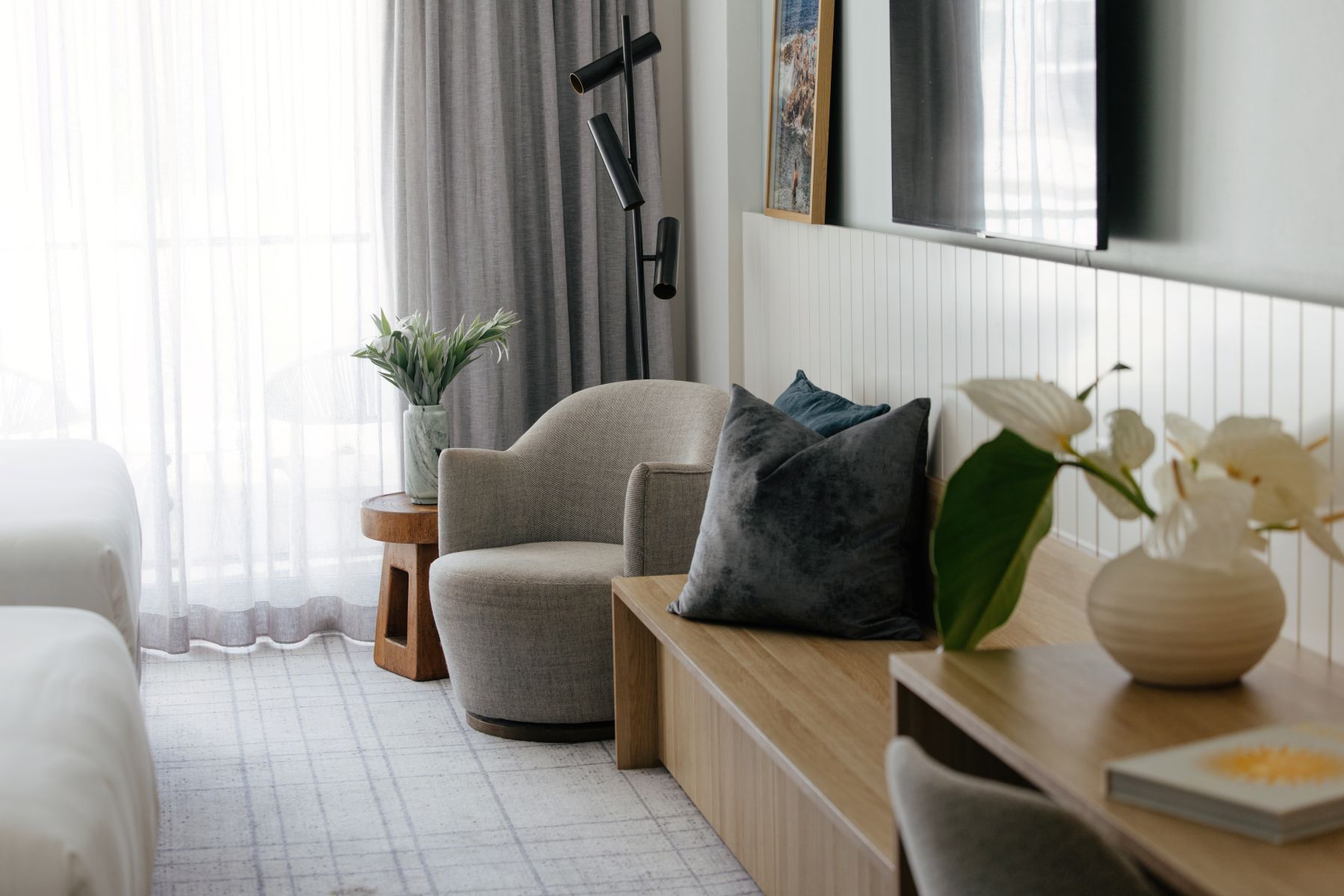 Uma sala de estar moderna com um sofá, uma mesinha de apoio com uma planta e um banco de madeira.