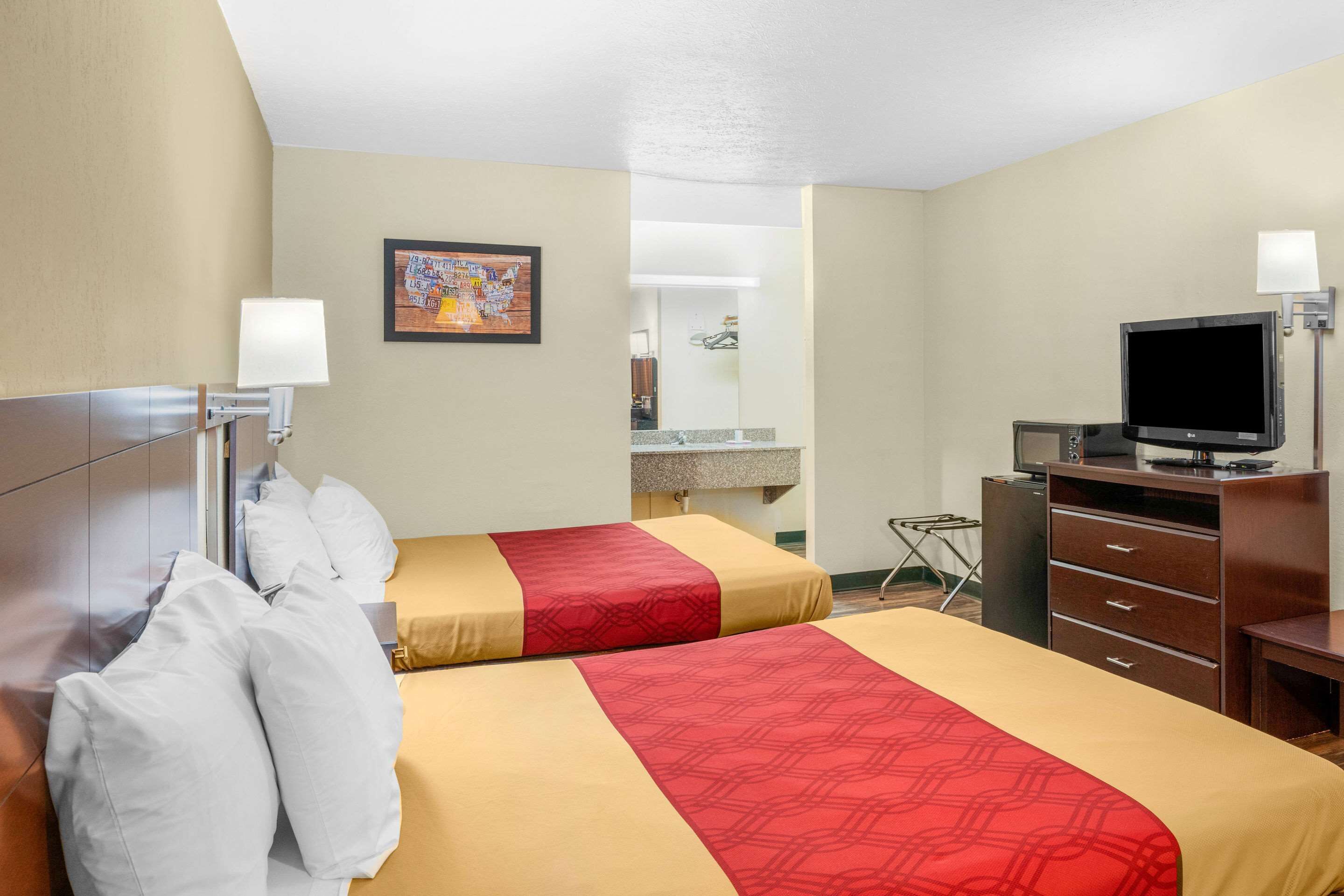 Quarto de hotel com duas camas, televisão, escrivaninha e espelho.