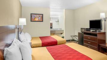 Quarto de hotel com duas camas, televisão, escrivaninha e espelho.