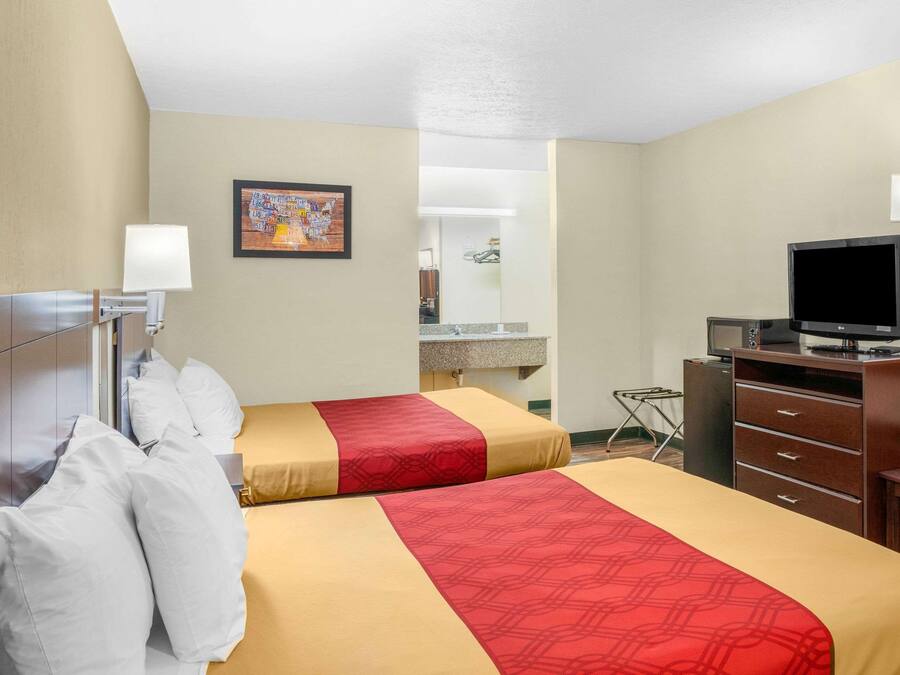 Quarto de hotel com duas camas, televisão, escrivaninha e espelho.