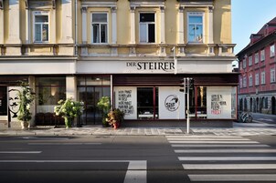 Um edifício com uma placa com a inscrição 'DER STEIERER' e um amplo vitrine.