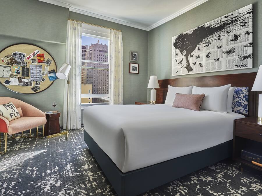 Quarto de hotel com uma cama grande, um mural redondo, vista para a cidade e design moderno.