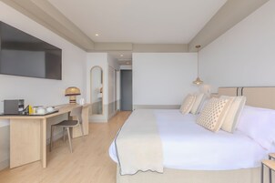 Quarto de hotel moderno com uma cama grande, uma escrivaninha com cadeira, televisão de tela plana e abajur.