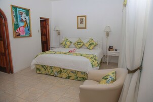 Um quarto com uma cama, duas mesas de cabeceira, uma cadeira e um quadro na parede.