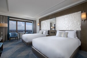 Quarto de hotel com duas camas, vista para a cidade e uma janela grande.