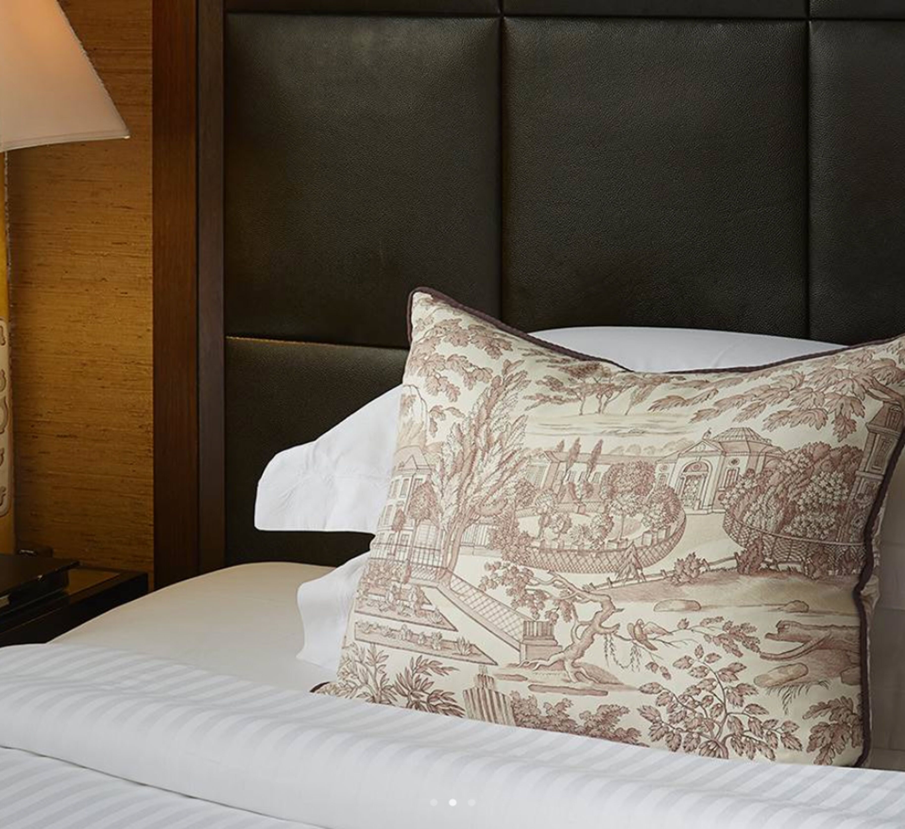 Cama com colchão branco e almofada decorativa com paisagem.