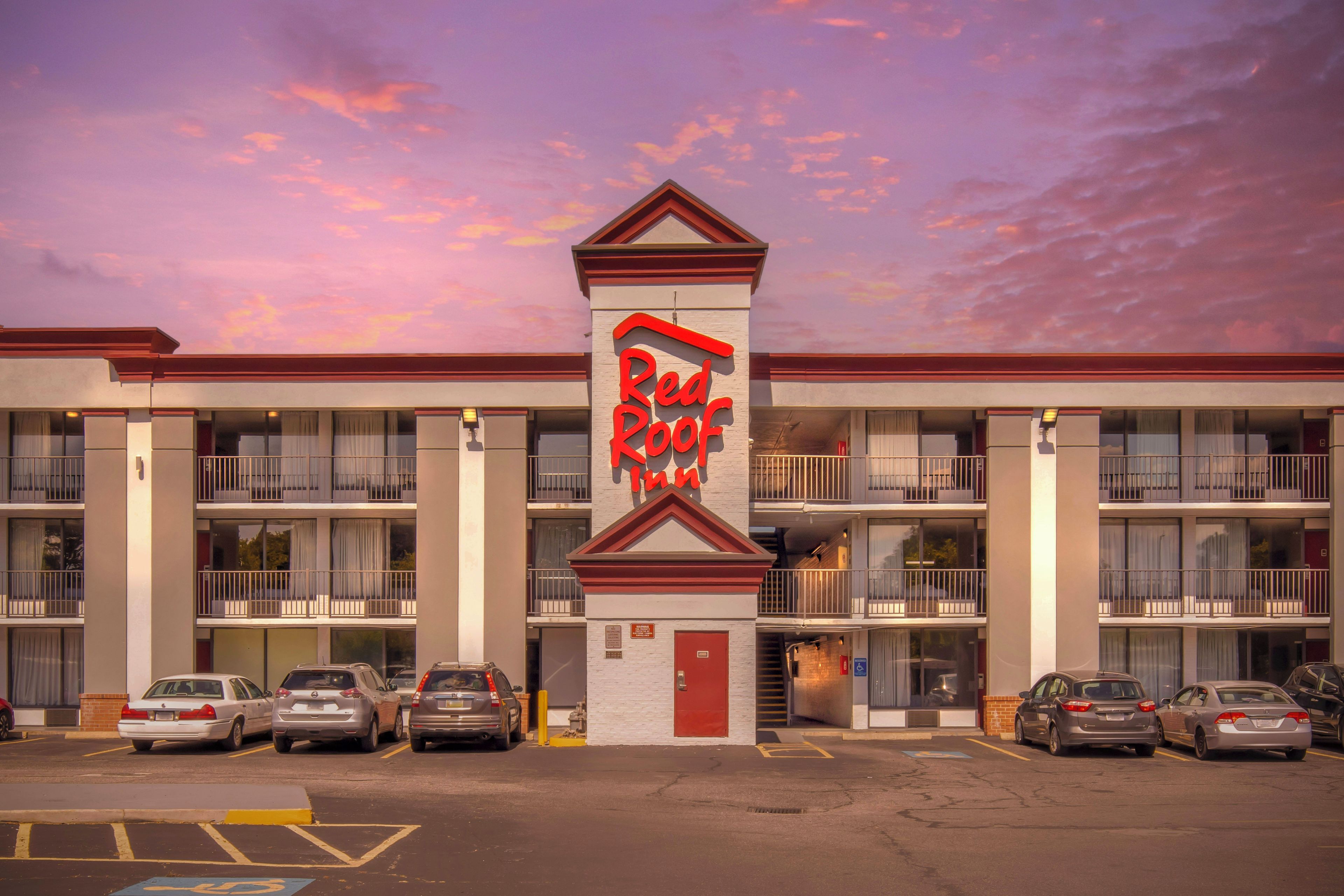 Um hotel com vários andares e uma placa vermelha chamativa com a inscrição 'Red Roof Inn'.