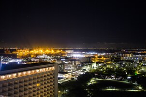 Paisagem urbana noturna com áreas industriais e edifícios iluminados.
