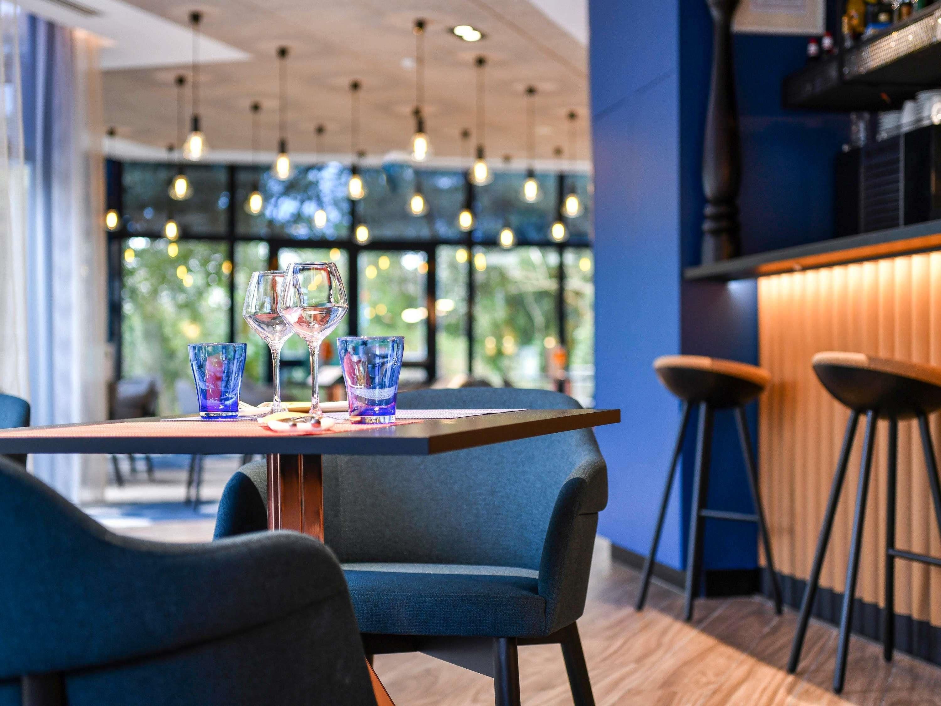 Uma área de bar com mesa, cadeiras e luminárias pendentes.