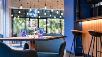 Uma área de bar com mesa, cadeiras e luminárias pendentes.