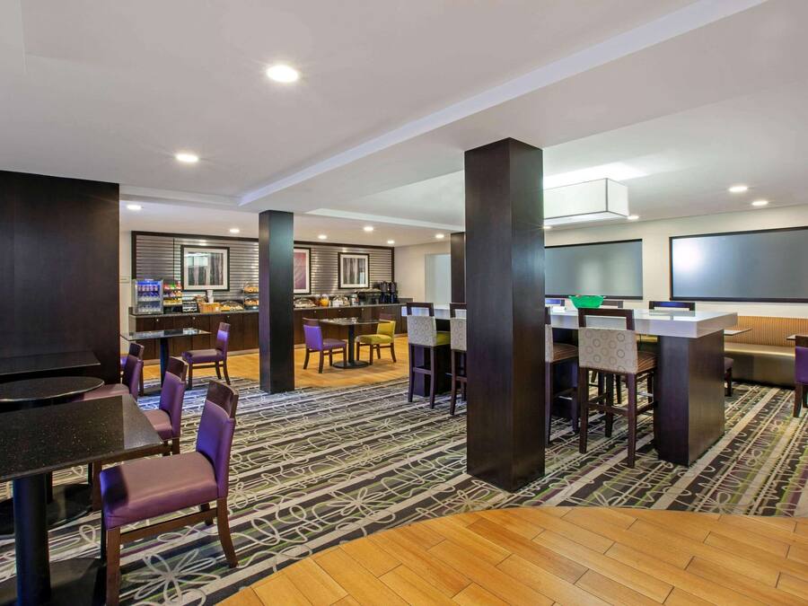 Um hall de hotel moderno com área de bar, assentos e balcão de recepção.