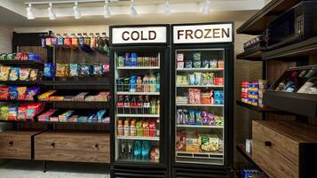 Vitrine refrigerada com seções identificadas como 'FRIO' e 'CONGELADO', contendo diversos lanches e bebidas.