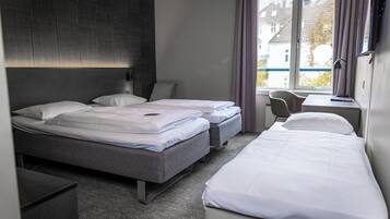 Quarto de hotel com duas camas, uma escrivaninha e uma cadeira.