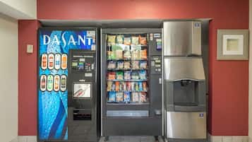 Máquina de vendas com diversos snacks e bebidas, um bebedouro e uma porta com design azul e branco.