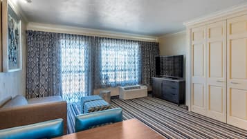 Quarto de hotel com área de refeições, televisão e armário.