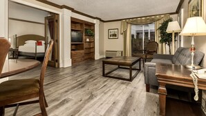 Uma sala de estar com piso de madeira, um sofá, uma mesa de centro, uma televisão e uma estante de livros.