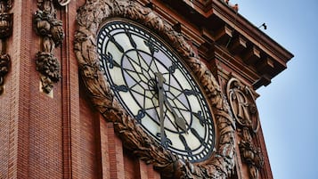 Um relógio grande e ornamentado, com esculturas detalhadas em um edifício de tijolos.