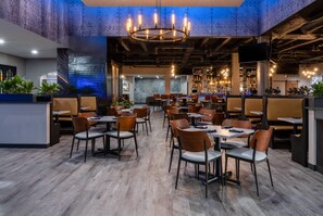 Um restaurante moderno com piso de madeira, detalhes em metal e uma área de bar.