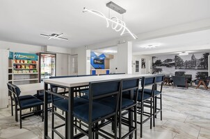 Um hall moderno de hotel com balcão de recepção, área de estar e televisão na parede.