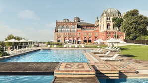 Um edifício grande com piscina, espreguiçadeiras e guarda-sóis.
