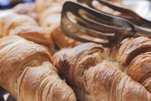 Close-up de croissants dourados e crocantes com textura brilhante e escamosa.