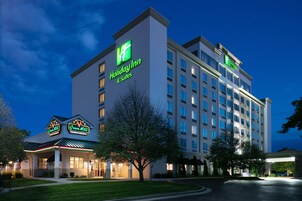 Um hotel Holiday Inn com design moderno, apresentando um logotipo verde marcante e sinalização para o Holiday Inn & Suites.