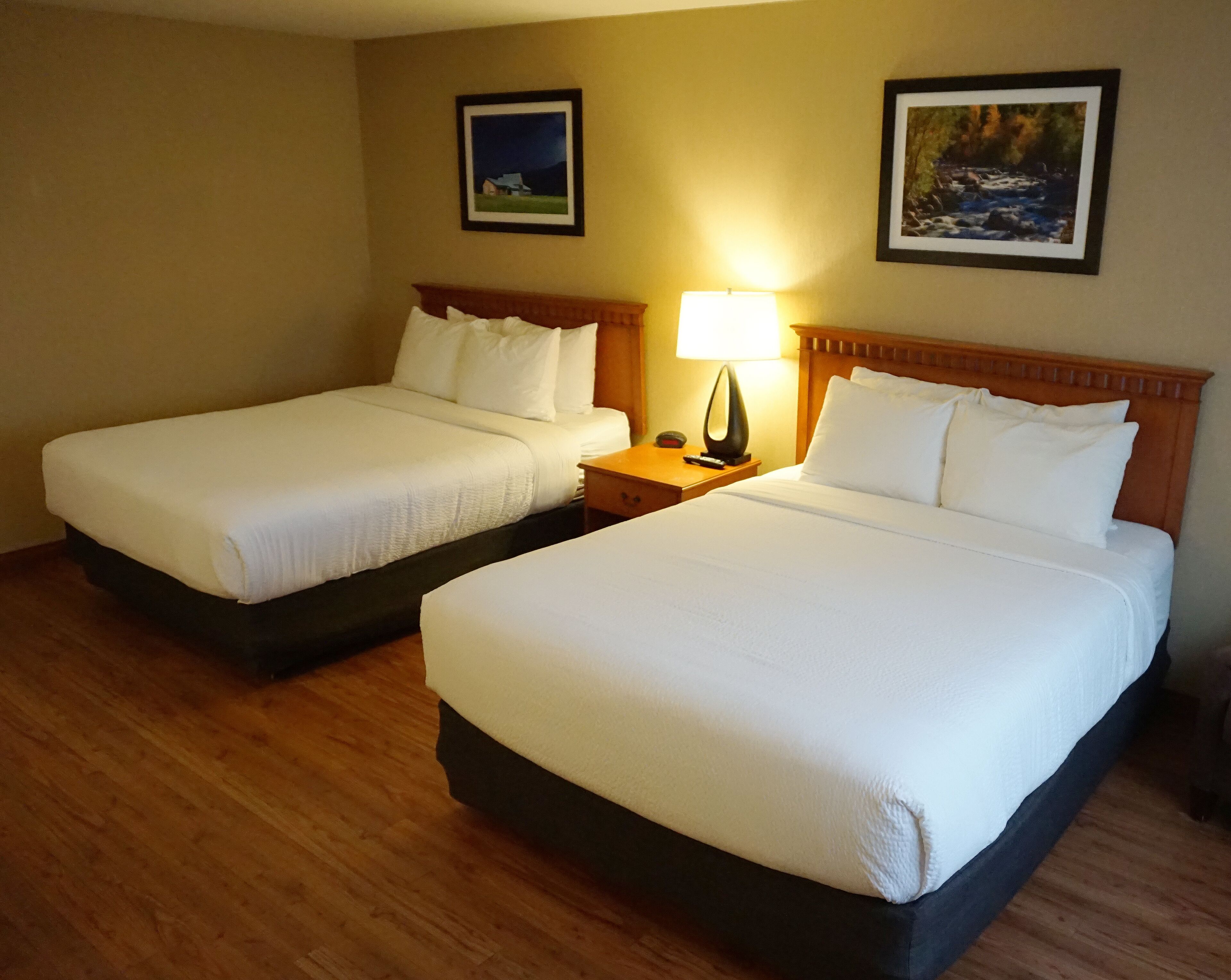 Duas camas de solteiro com cabeceiras de madeira num quarto de hotel.