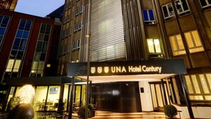Um hotel moderno com fachada imponente, vários andares e uma entrada destacada com a placa 'UNA Hotel Century'.
