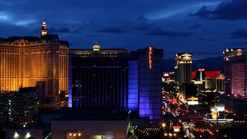 Paisagem urbana noturna com edifícios iluminados, incluindo um hotel de destaque com uma torre acesa.