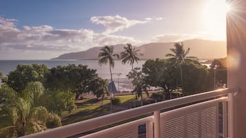 Varanda com vista para o oceano e palmeiras.