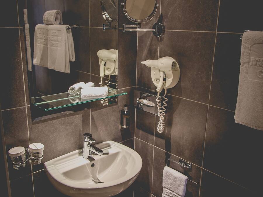 Casa de banho com lavatório, espelho, toalheiro e secador de cabelo.