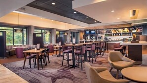 Um restaurante moderno com várias áreas de estar, incluindo cabines e mesas, e um bar com diversas bebidas.
