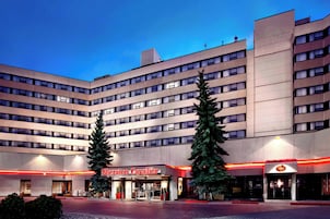 Um hotel com design moderno, apresentando uma entrada central com uma placa que diz 'Sheraton Cavalier'.